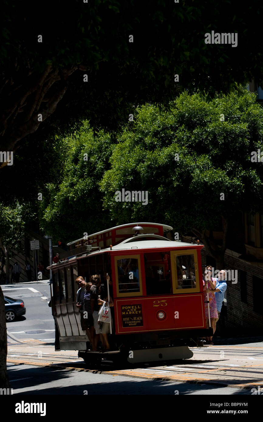 Red cable car ascending tree lined Powell Street in San Francisco ...