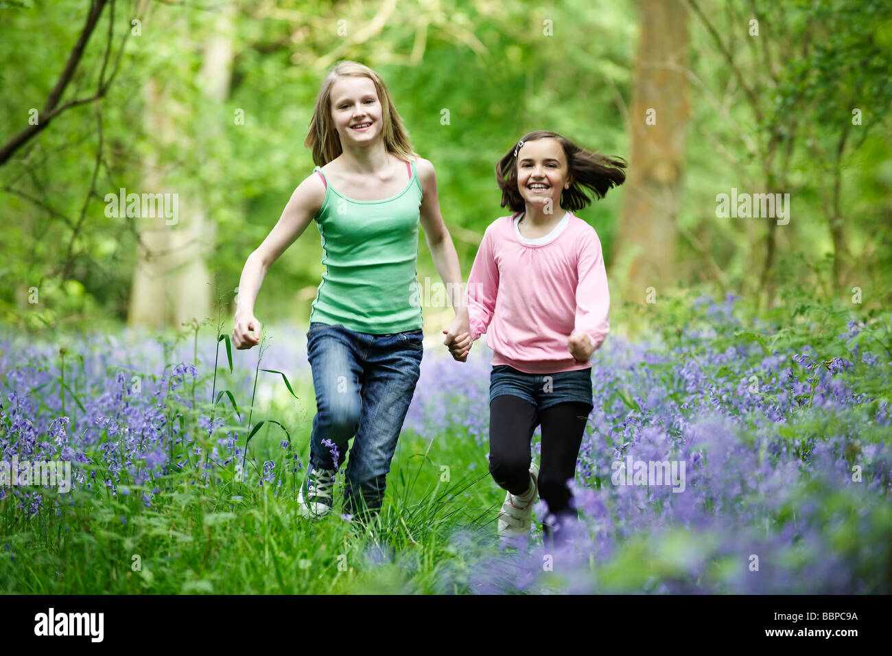 young girls running towards camera in a wood full of bluebells Stock ...
