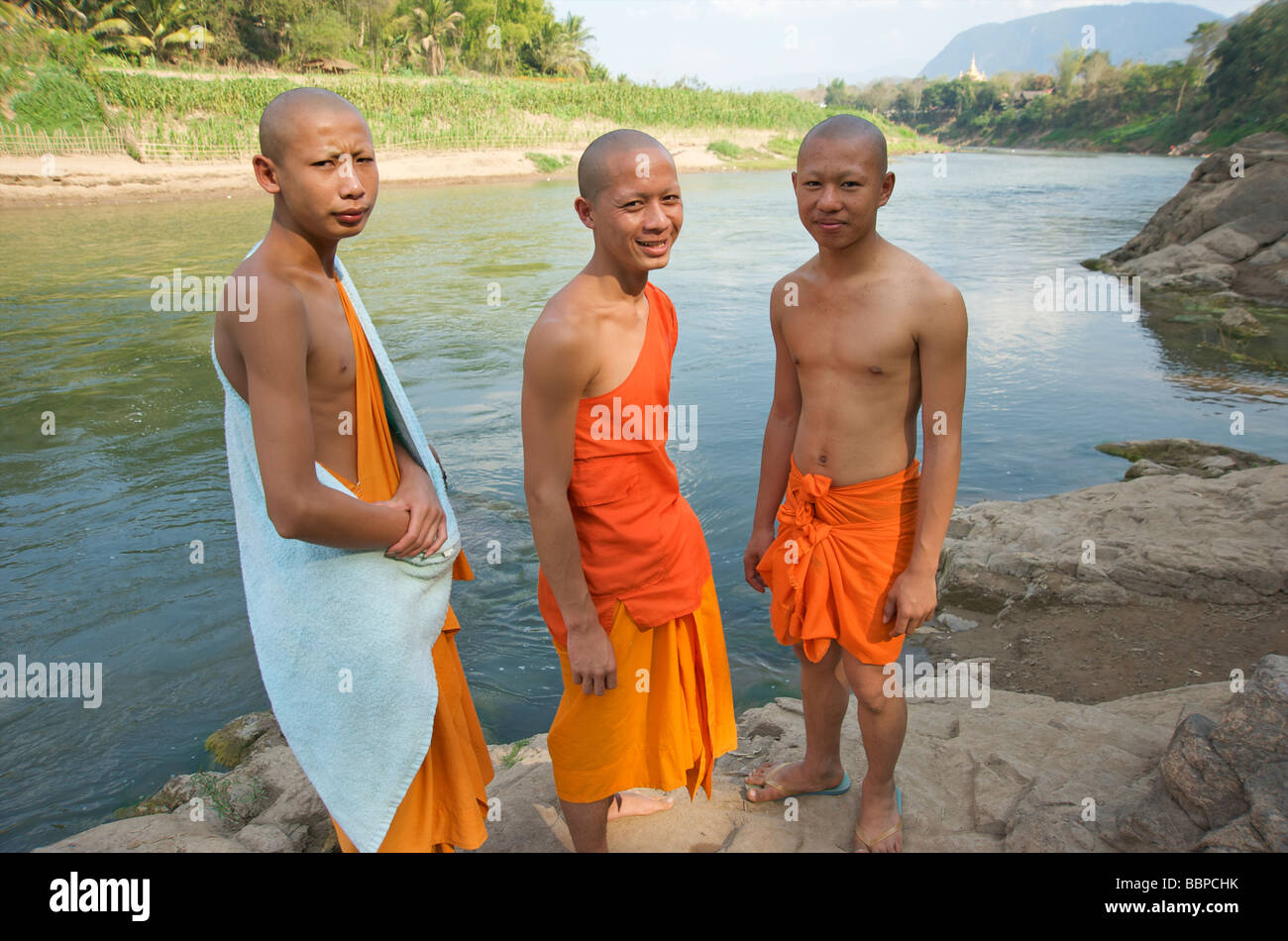 Three novice Buddhist monks preparing for a swim in the Nam Khan river ...