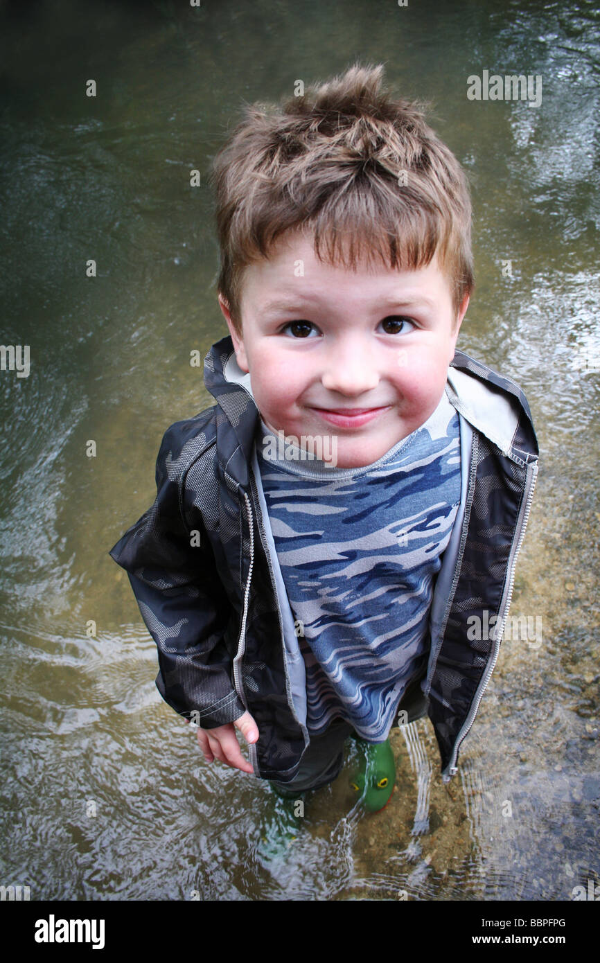 boy looking up standing in stream wearing wellies Stock Photo - Alamy