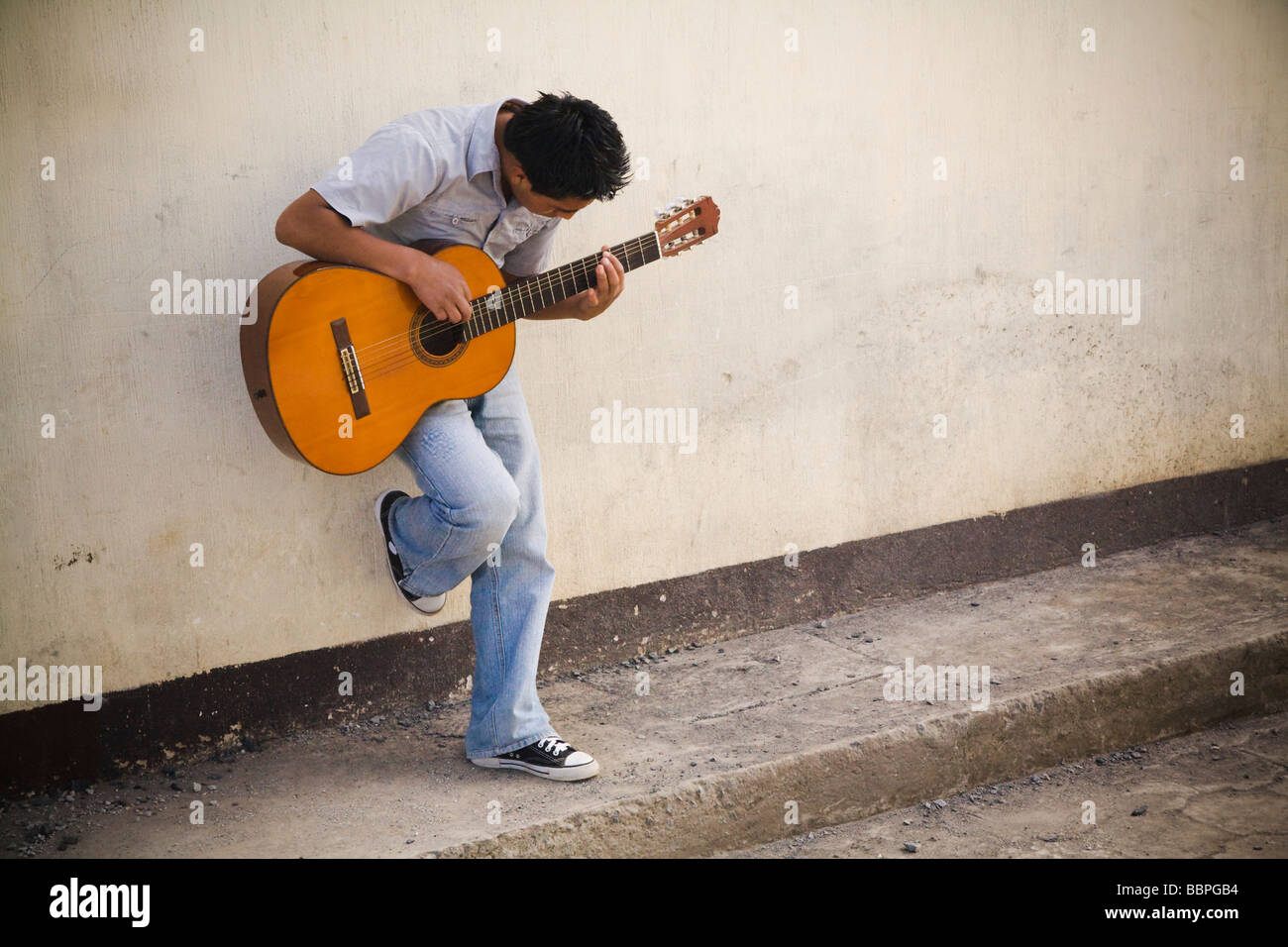 Patzicia,Guatemala;Man leaning against a wall playing guitar Stock ...