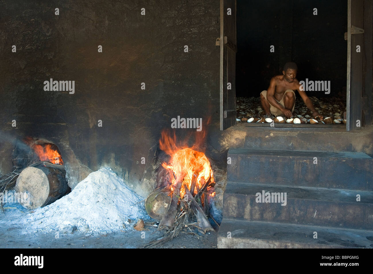 Worker drying coconuts over a heated grill to produce copra Quelimane ...