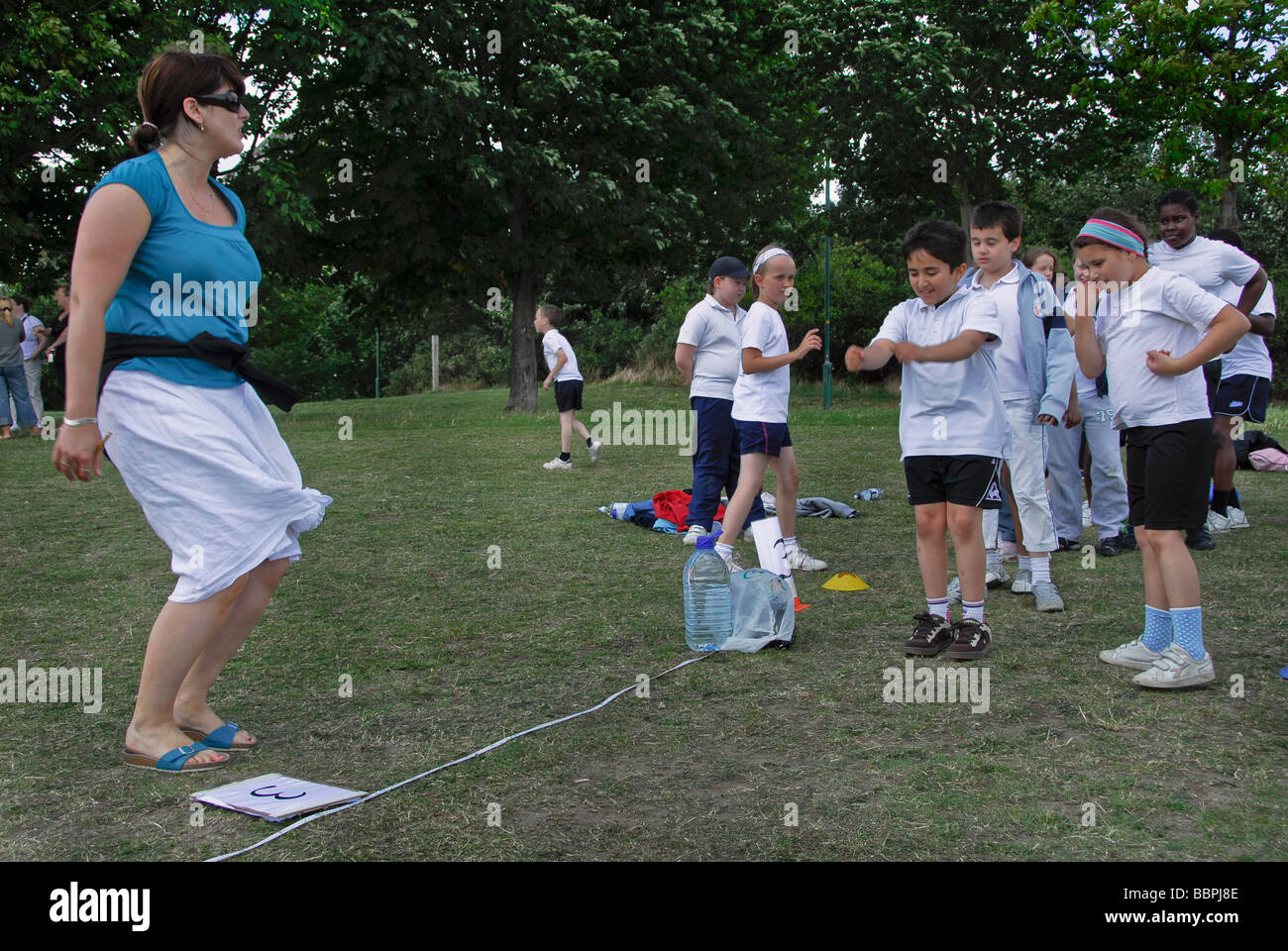 PRIMARY SCHOOL PUPIL PREPARING FOR THE JUMP WHILE HIS TEACHER OBSERVING ...