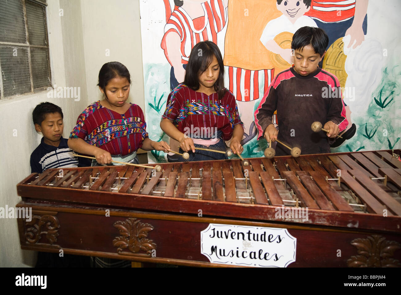 Guatemala;Children playing the xylophone in front of a colorful mural ...