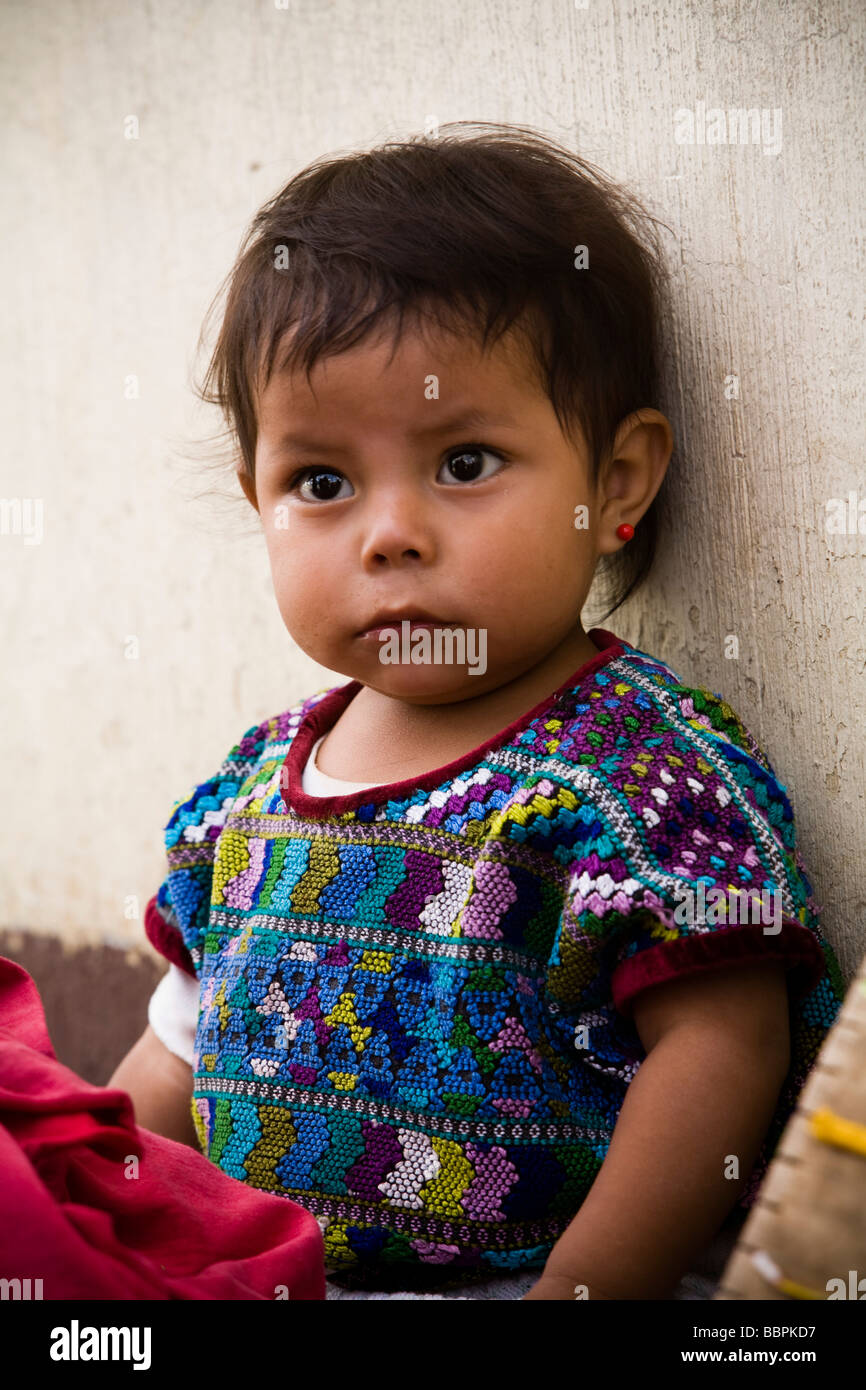 Guatemala;Baby girl sitting against a wall Stock Photo - Alamy