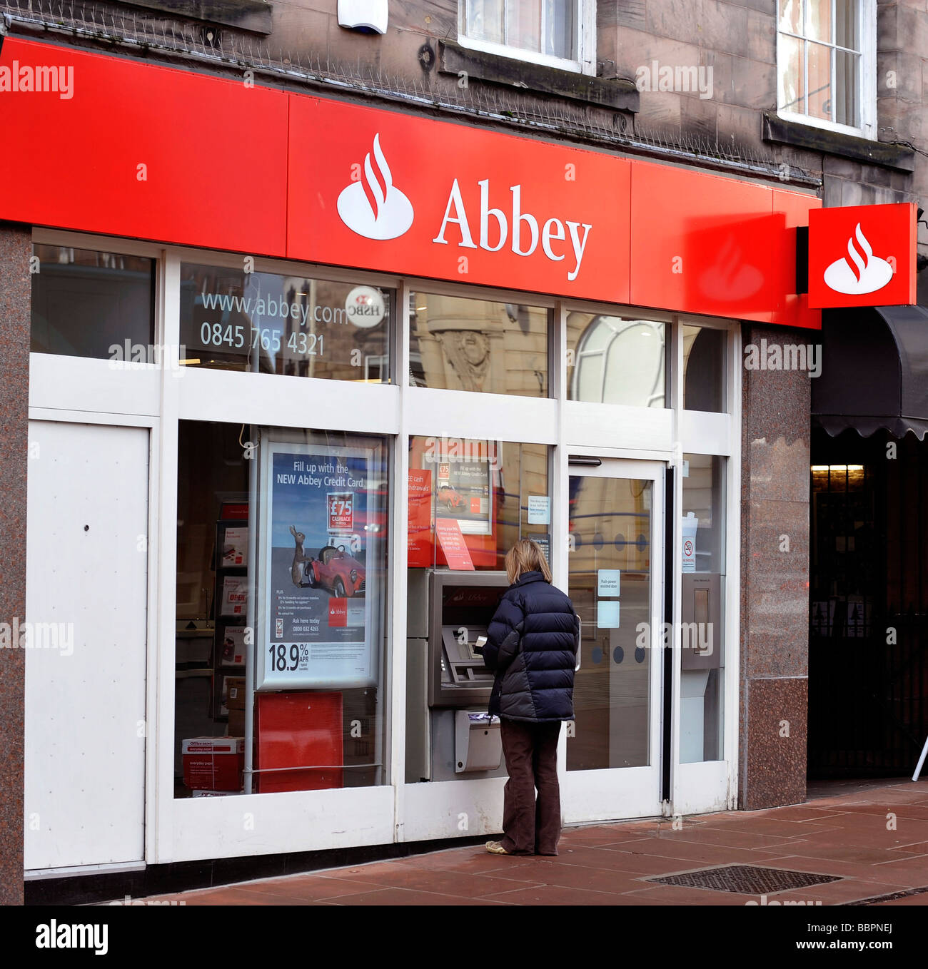 A woman uses an ATM cashpoint machine at a branch of Abbey Building ...