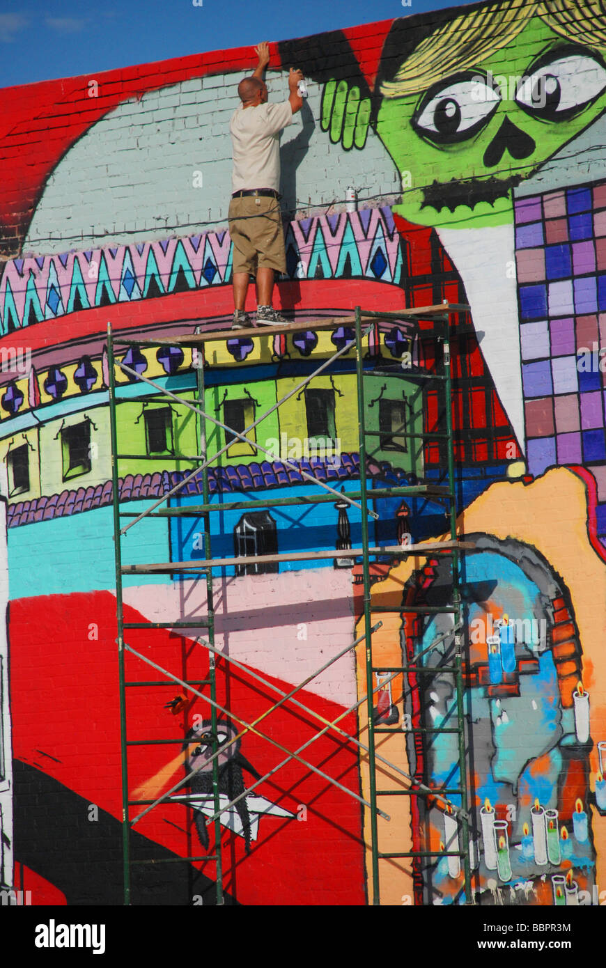 Man painting graffiti on the side of a building Stock Photo - Alamy