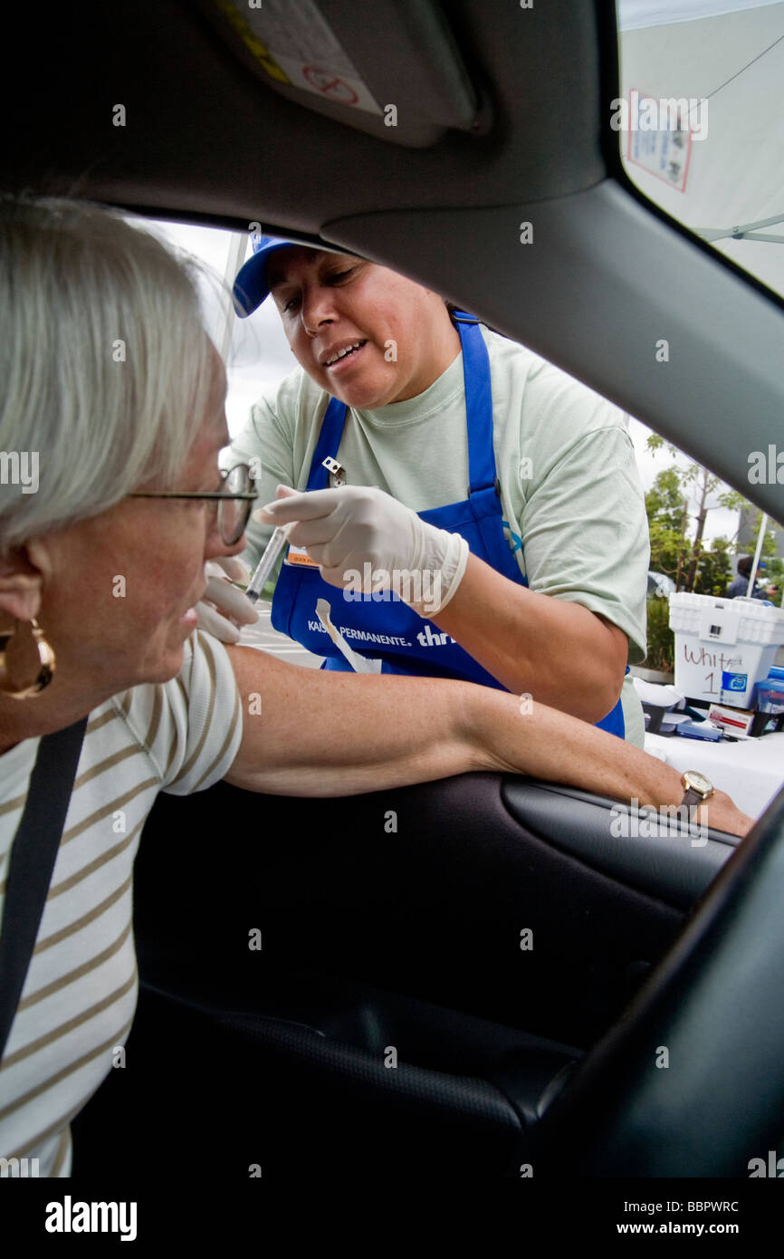 A Hispanic medical technician administers drive through flu shots to a ...