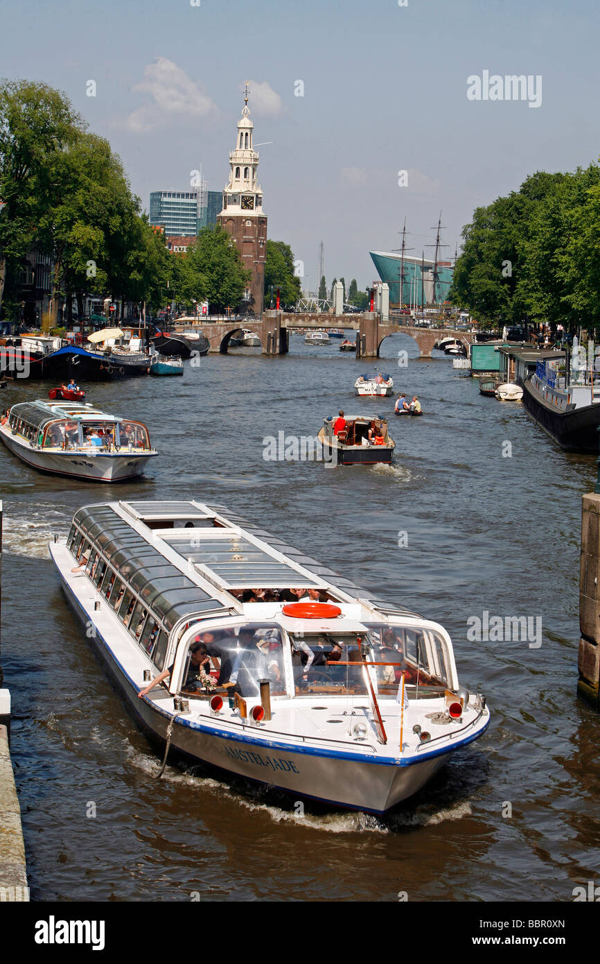 SIGHTSEEING BOAT AND PLEASURE BOAT ON A CANAL AND THE MONTELBAANSTOREN ...