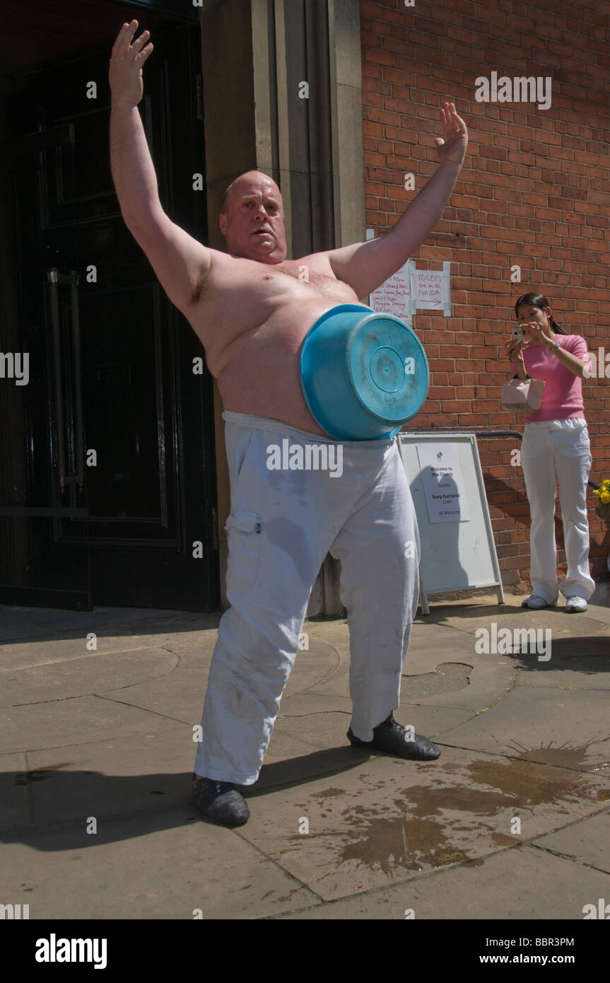 Fat man stands up holding blue bowl with his stomach and calls for ...