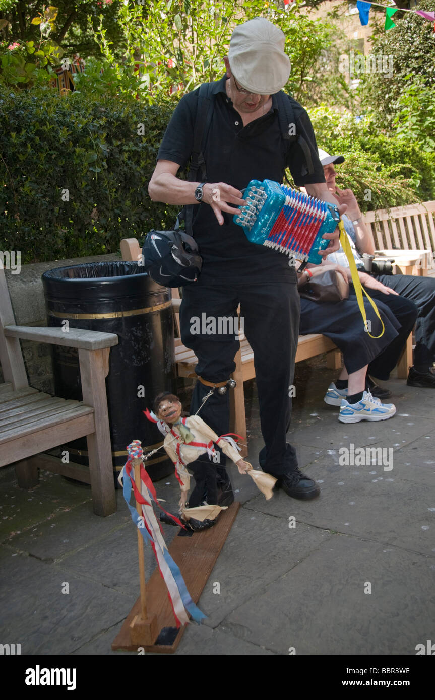 Man plays concertina and works puppet with knee and foot at Covent ...