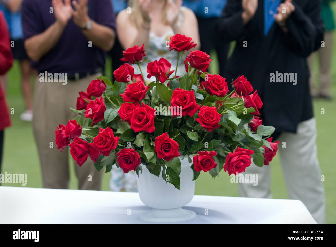 People clap in background with vase of roses during an awards ceremony ...