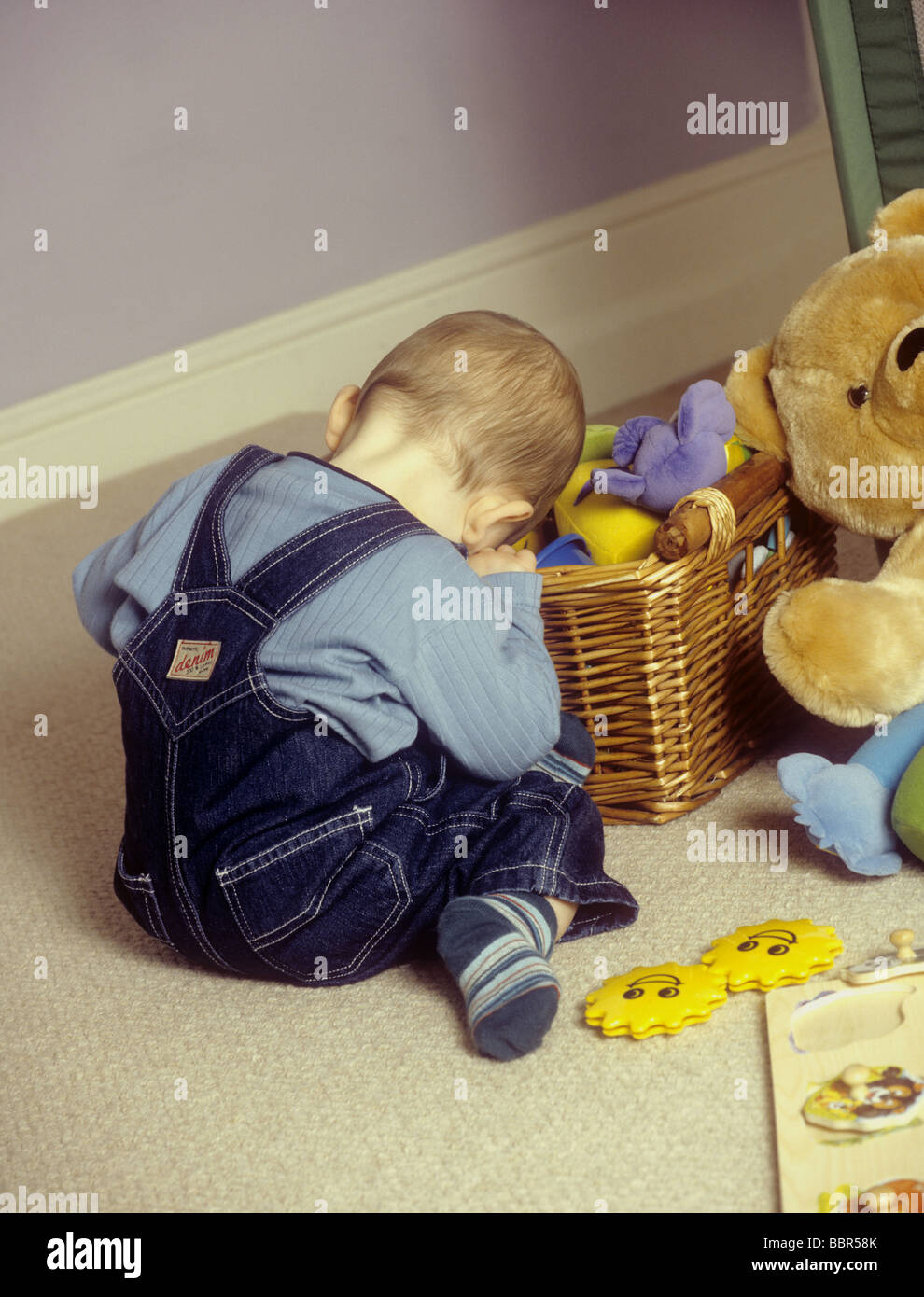 Baby boy with toys resting his head on his hands, tired, unhappy ...