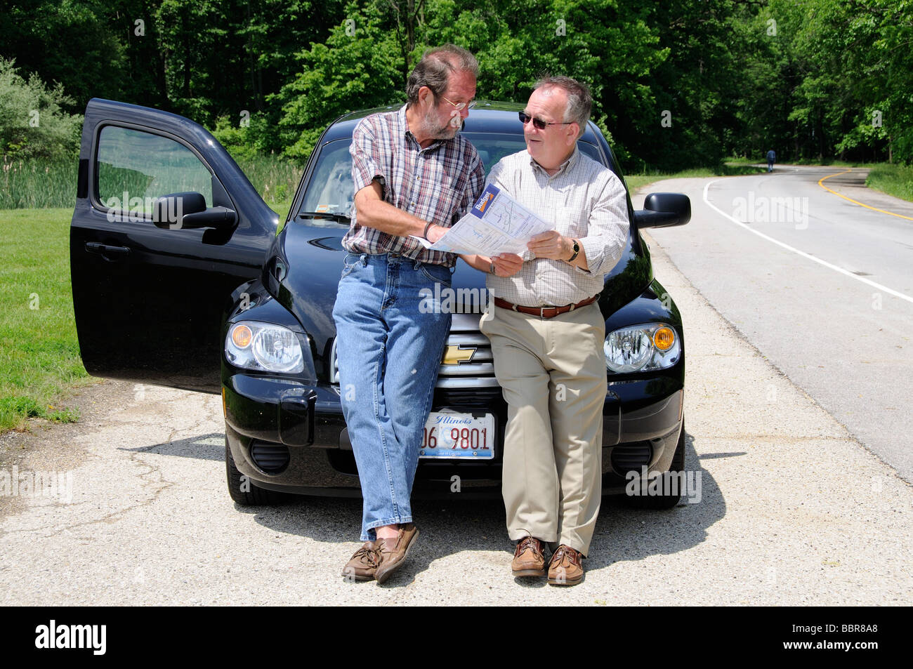 Two men with a rental car sitting on the bonnet map reading USA Stock ...