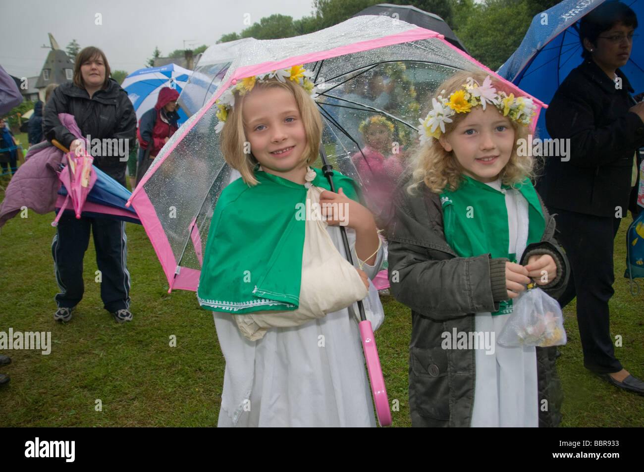 Two young members of a May Queen realm shelter under an umbrella at the ...