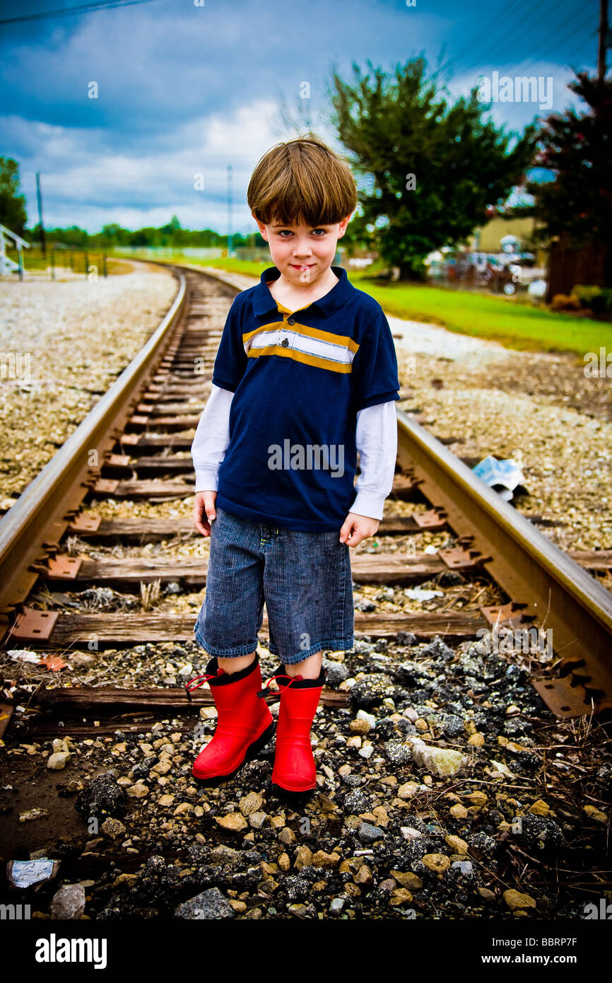 boy on train tracks with red boots Stock Photo - Alamy
