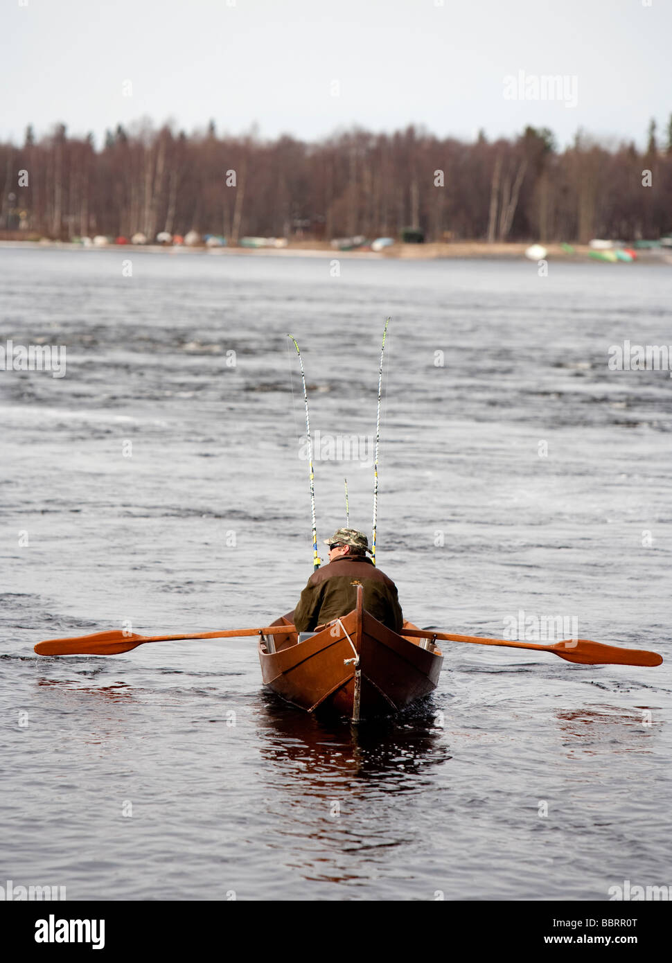 Fisherman trolling using a traditional wooden rowboat / skiff at River ...