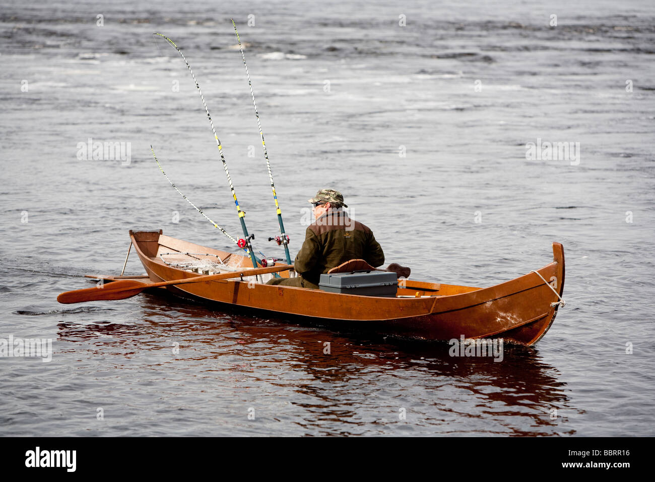 Fisherman trolling using a traditional wooden rowboat / skiff at River ...