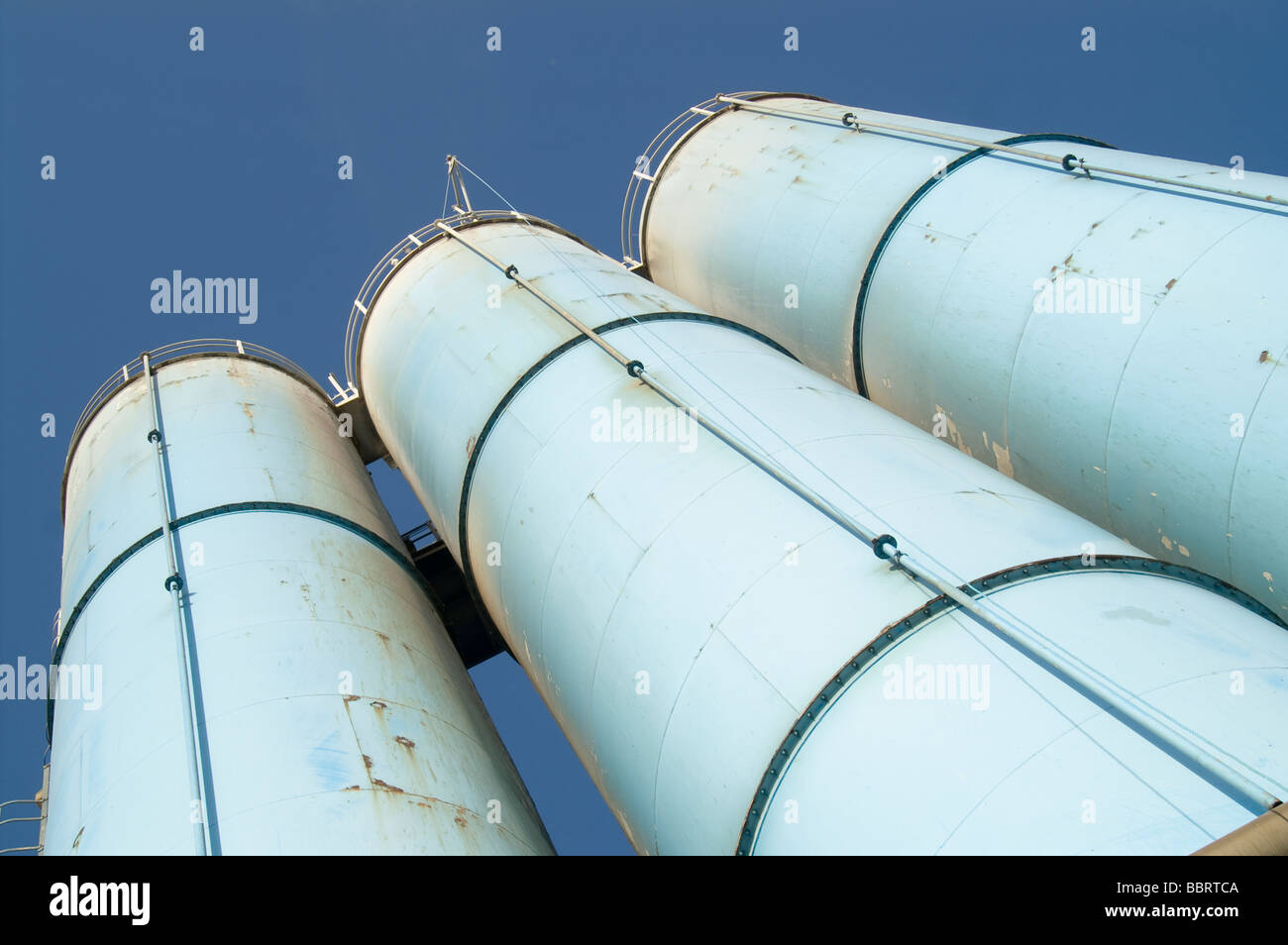 Three industrial light blue silos against blue sky Stock Photo - Alamy