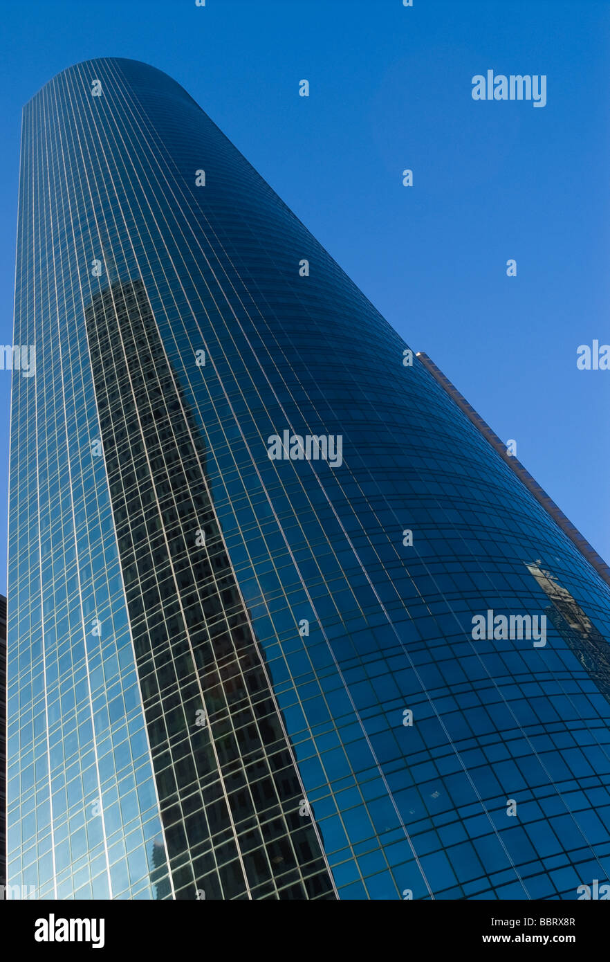 Skyscraper with reflection on blue glass windows against a clear sky ...