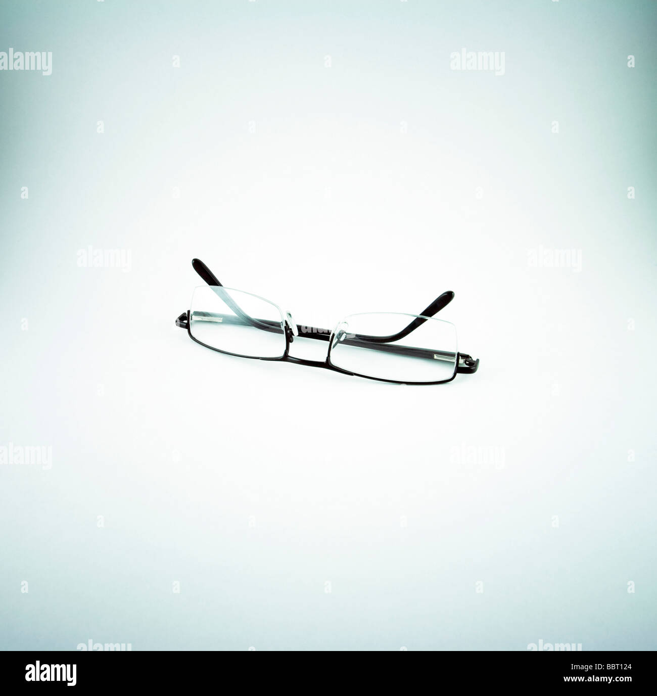 A pair of reading glasses/spectacles folded up on an isolated white ...