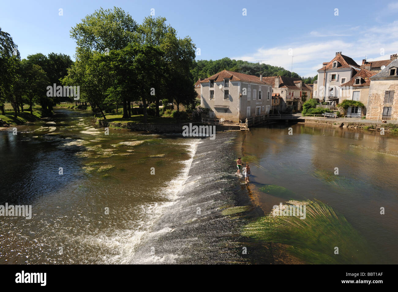 Boys playing on the weir of the River Auvezere in Cubjac Dordogne ...