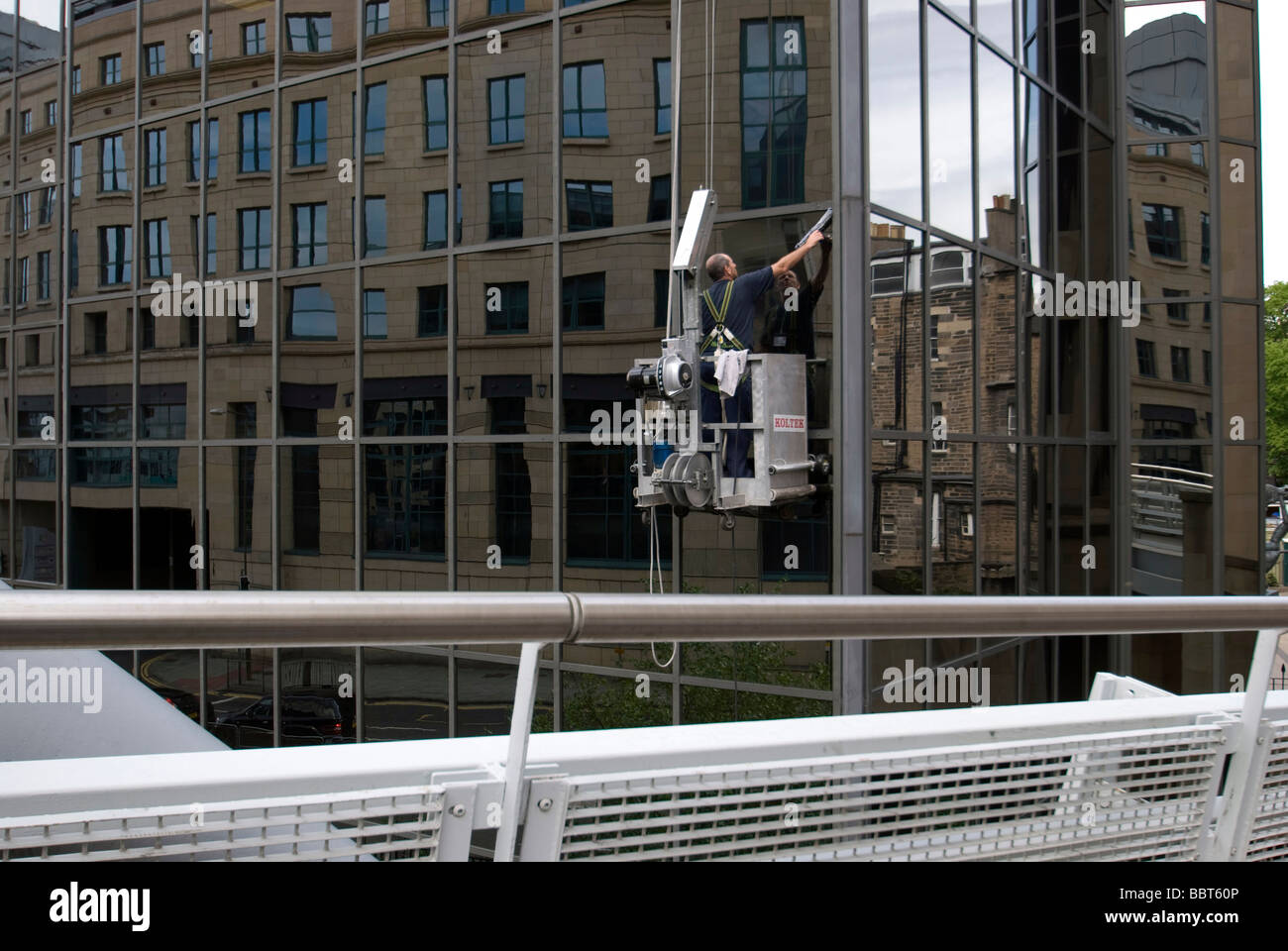 Window cleaner working on a modern building from a suspended cage Stock ...