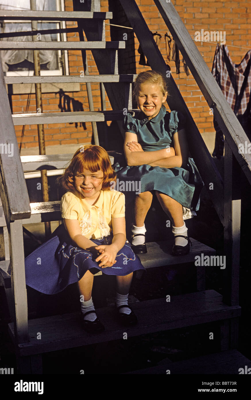 Happy 1950s children sitting on wooden steps in the sun 1957 Stock ...