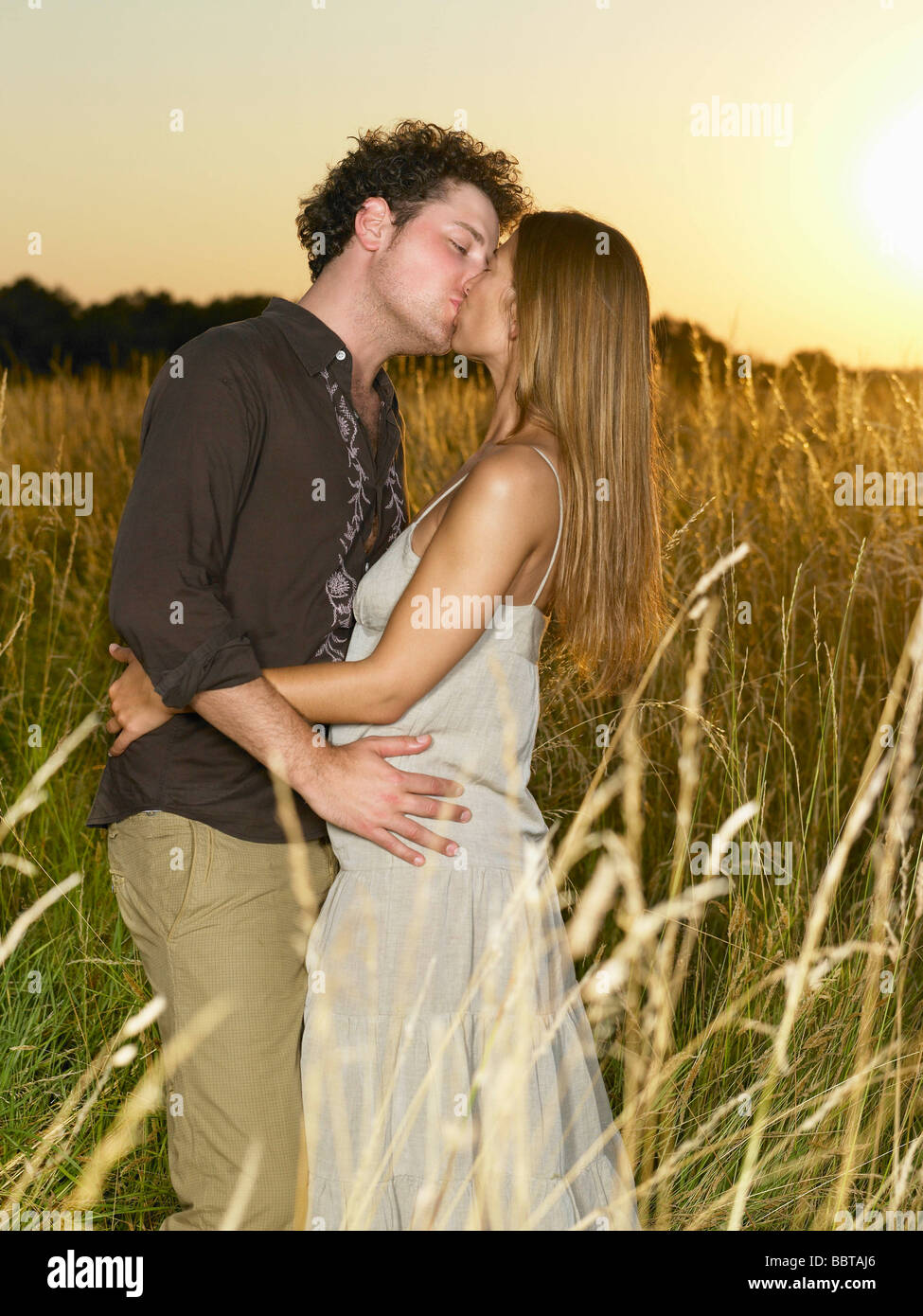 Couple kissing, in a field Stock Photo - Alamy