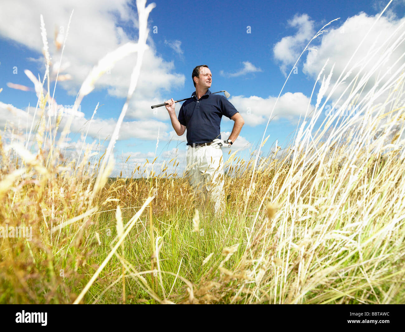 Man in a field with a golf club Stock Photo - Alamy