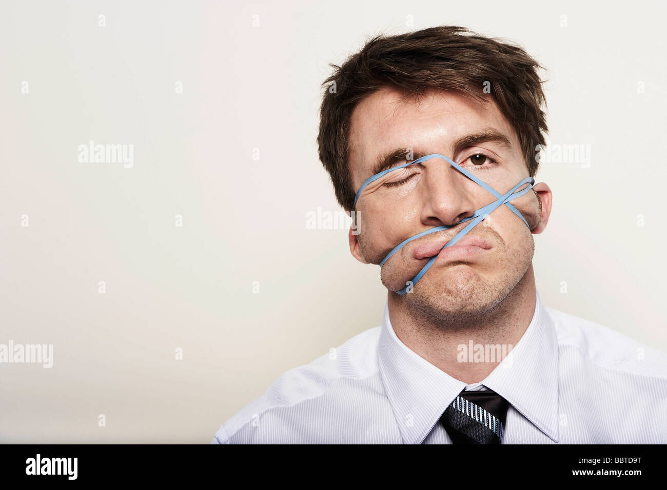 Business man with rubber bands on face Stock Photo - Alamy