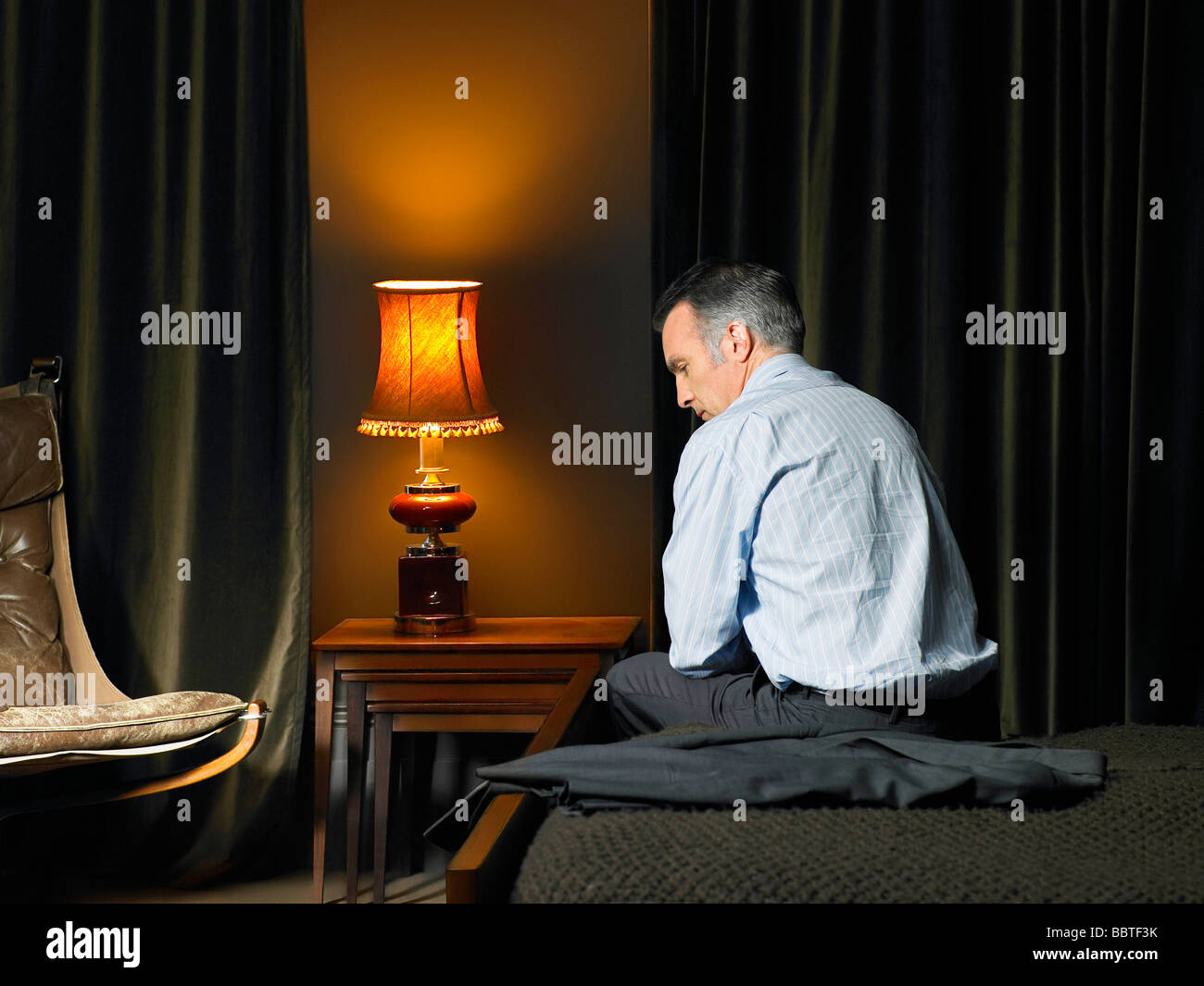 Man sitting on bed with back to camera Stock Photo - Alamy