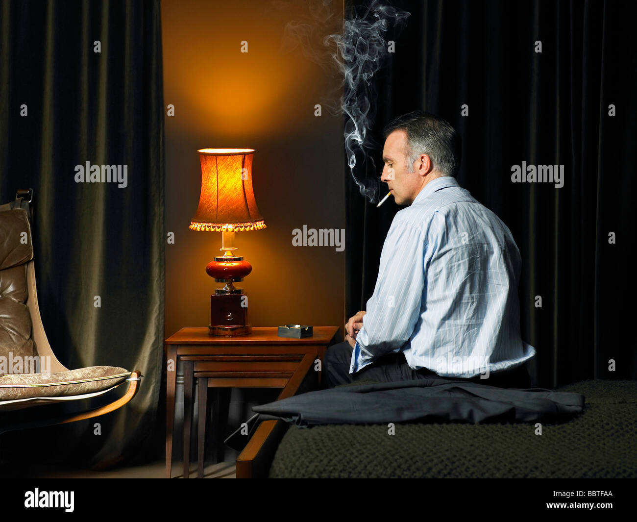 Man sitting on bed smoking a cigarette Stock Photo - Alamy