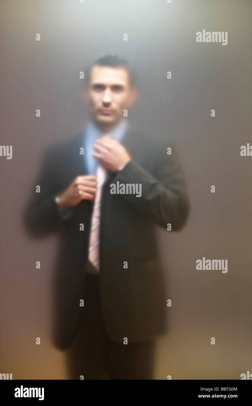 Man adjusting tie behind frosted screen Stock Photo - Alamy