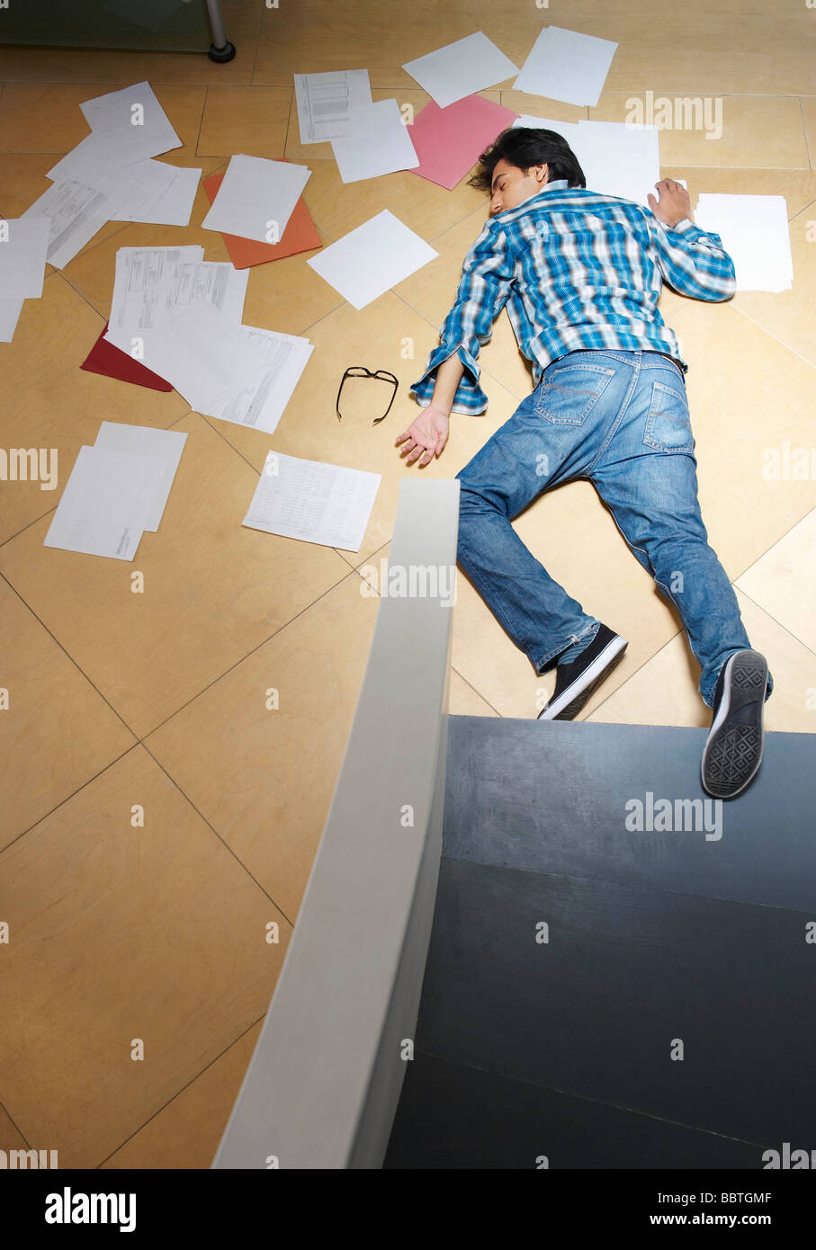 Young man lying on office floor Stock Photo - Alamy