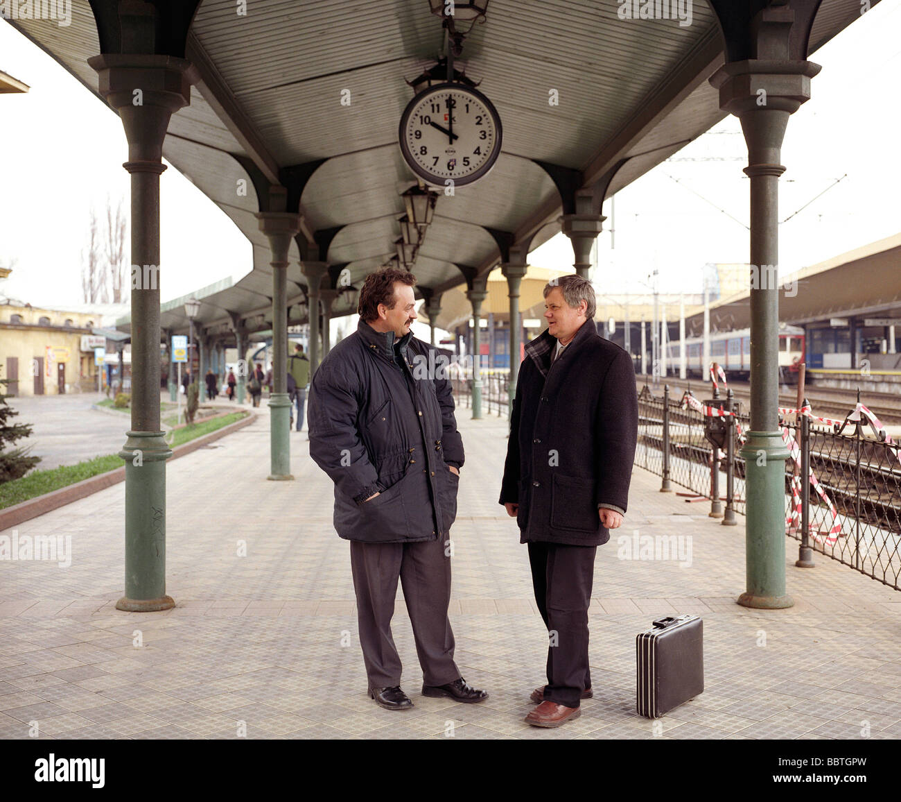 Two men talking on train platform Stock Photo - Alamy