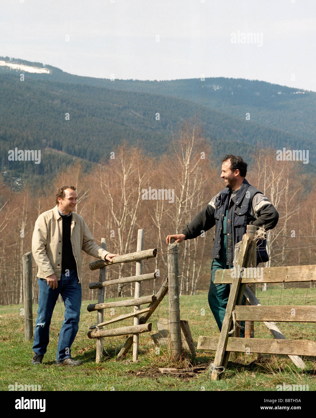 Two men talking over fence and gate Stock Photo - Alamy