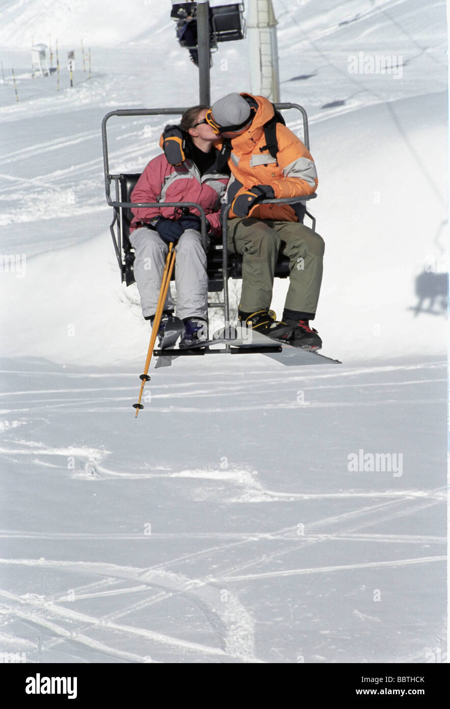 Couple sitting on chair lift, kissing Stock Photo - Alamy