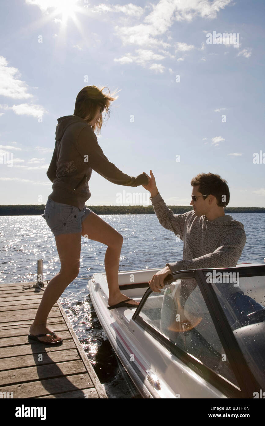 Couple climbing into speedboat Stock Photo - Alamy