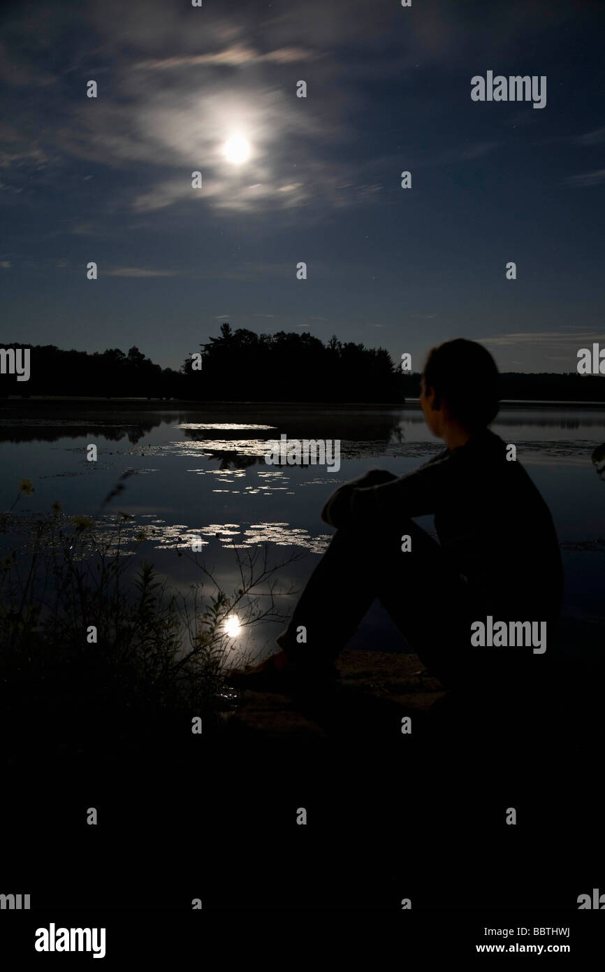 Woman watching moon over lake Stock Photo - Alamy