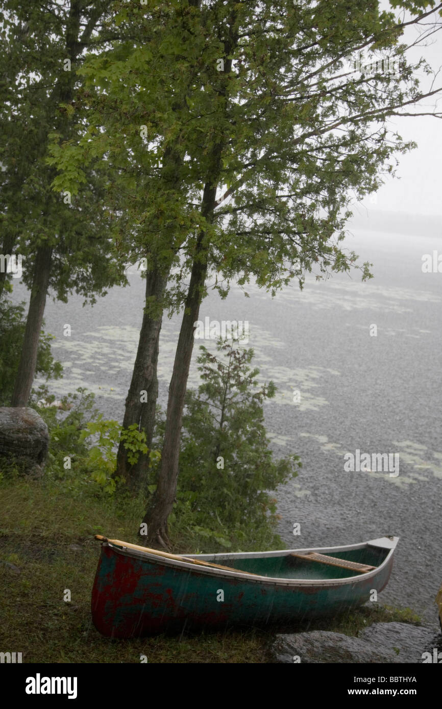 Canoe in rain by lake Stock Photo - Alamy