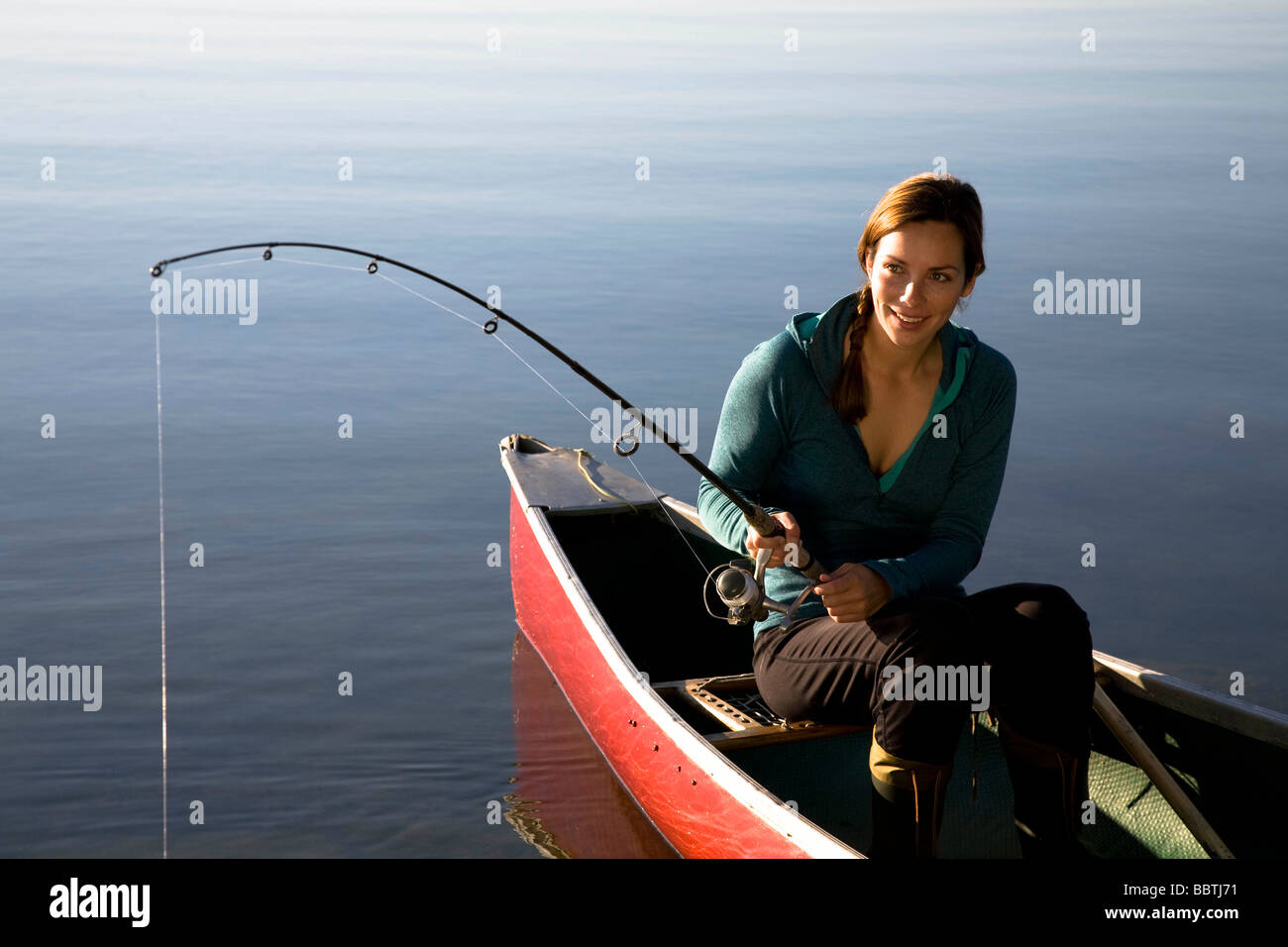 Woman fishing from canoe Stock Photo - Alamy