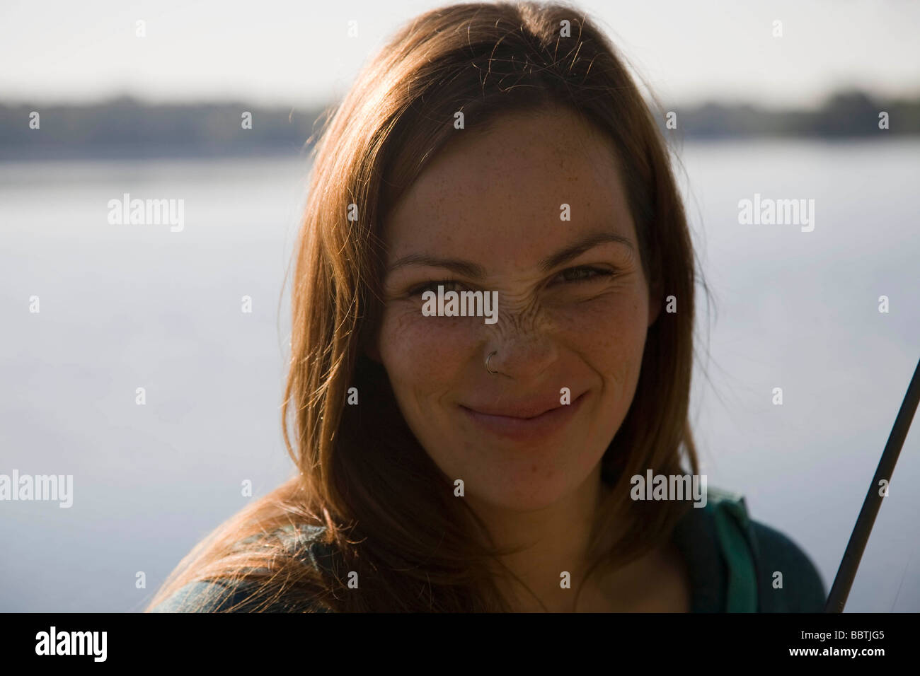 Woman squinting at camera whilst fishing Stock Photo - Alamy