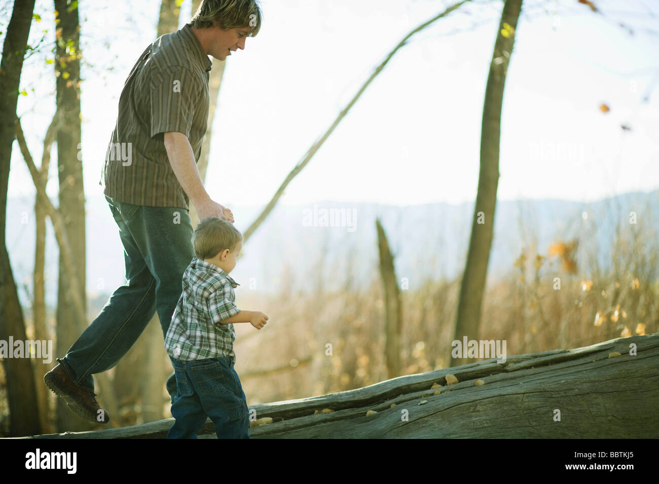 Father guiding young son on log Stock Photo - Alamy