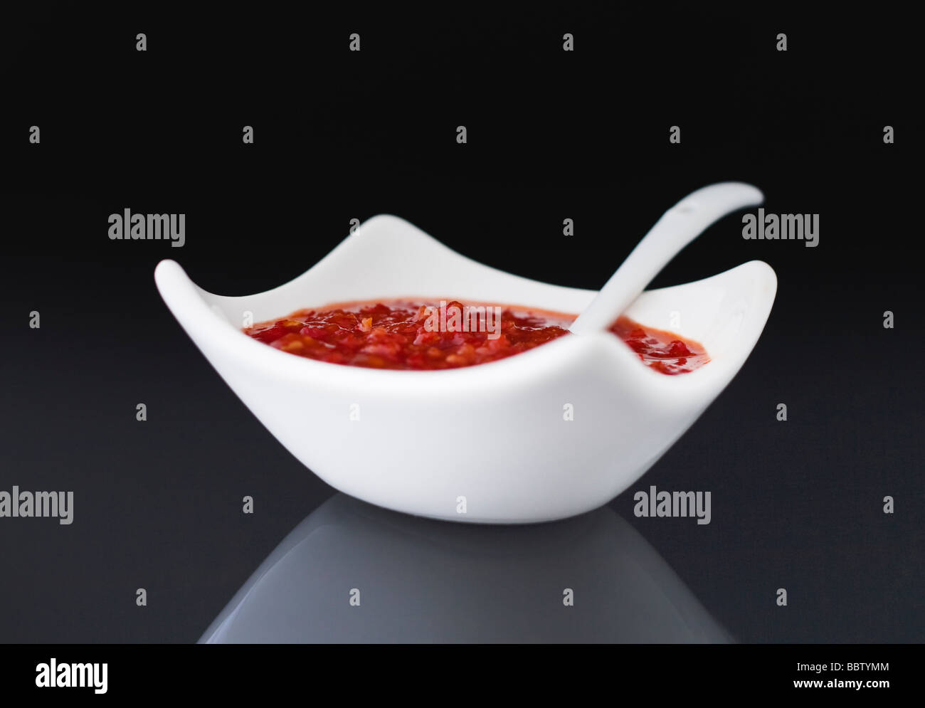 Chilli sauce in a white dish with serving spoon Stock Photo - Alamy