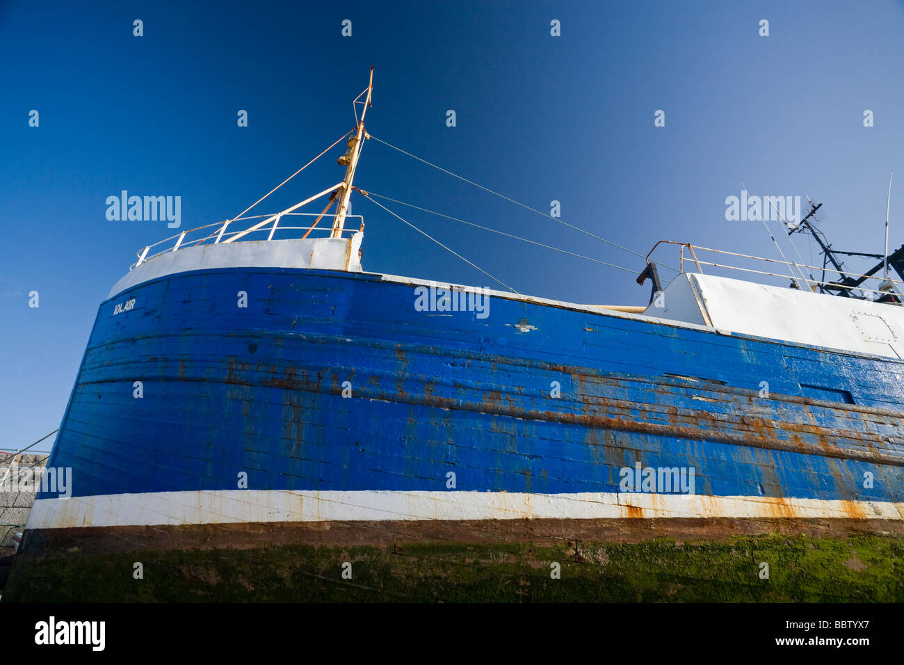 Beached Ship, blue on Blue. An old wooden ship beached in the harbour ...