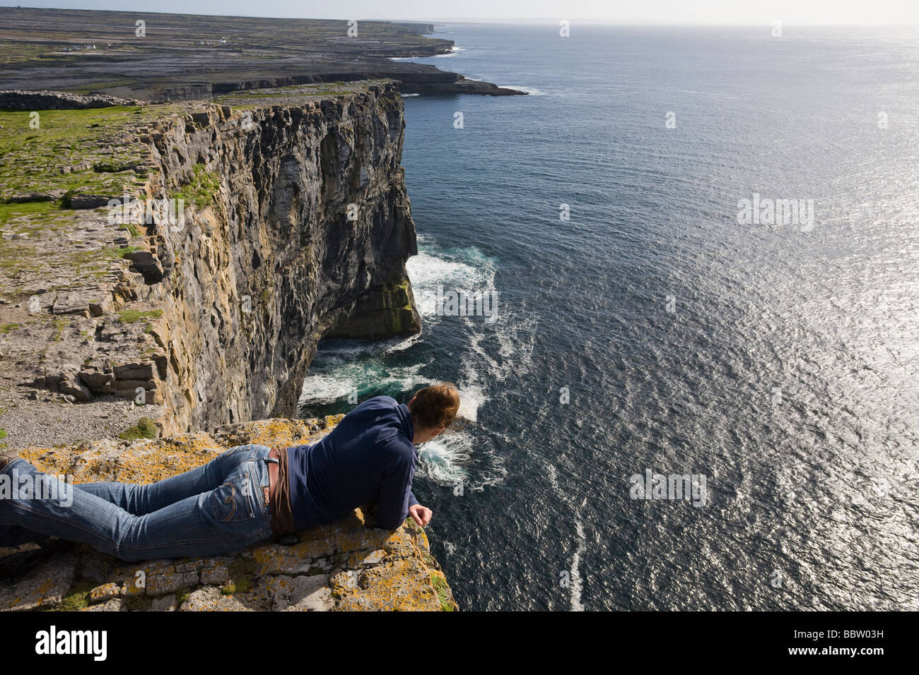 High View, Crashing Waves. A young woman leans over the 100 meter cliff ...