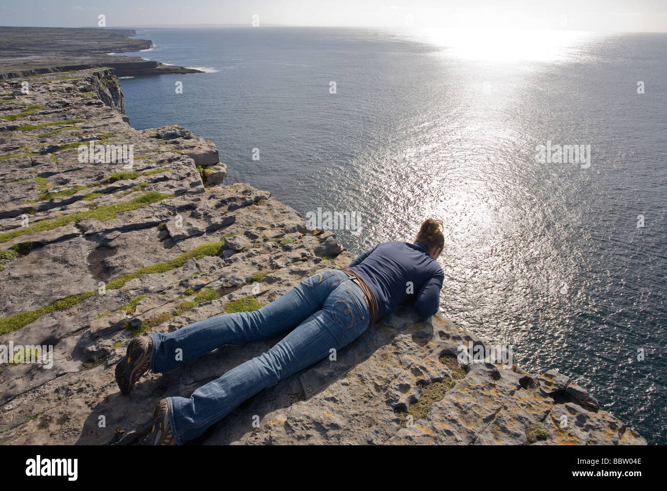 At the Edge. A young woman, echoing the lines in the rock, leans over ...