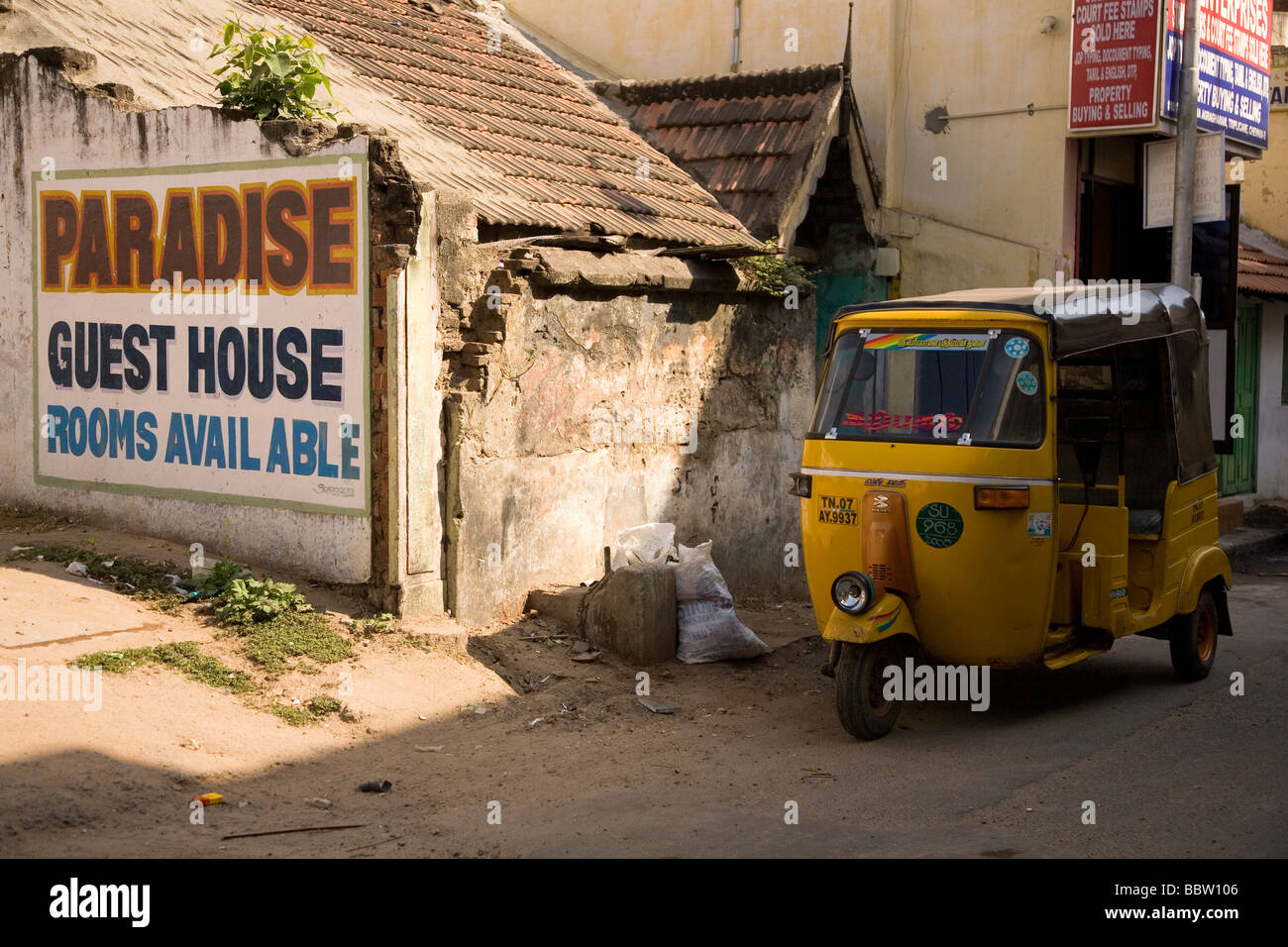 A rickshaw stands on a street in Chennai, India. A sign says that rooms ...