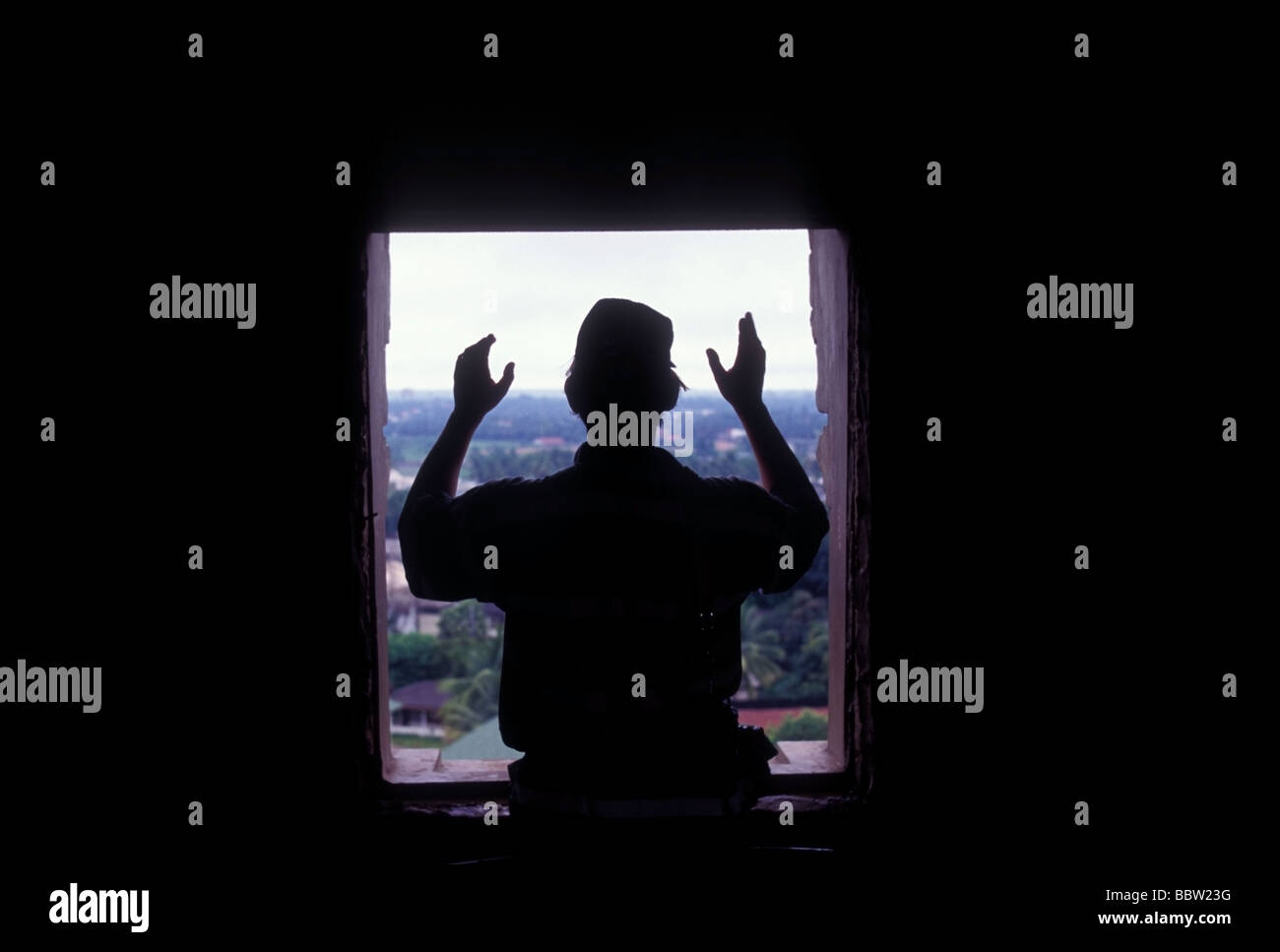 Silhouette of a man praying at a window with his hands raised Stock ...